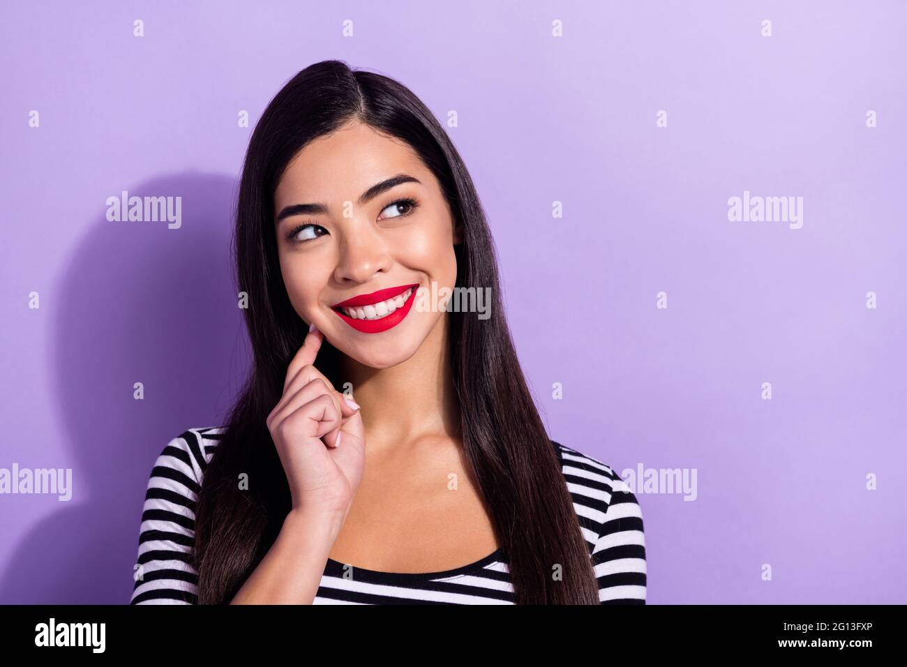 Photo Of Adorable Tricky Young Lady Wear Striped Shirt Smiling Finger Cheek Looking Empty Space