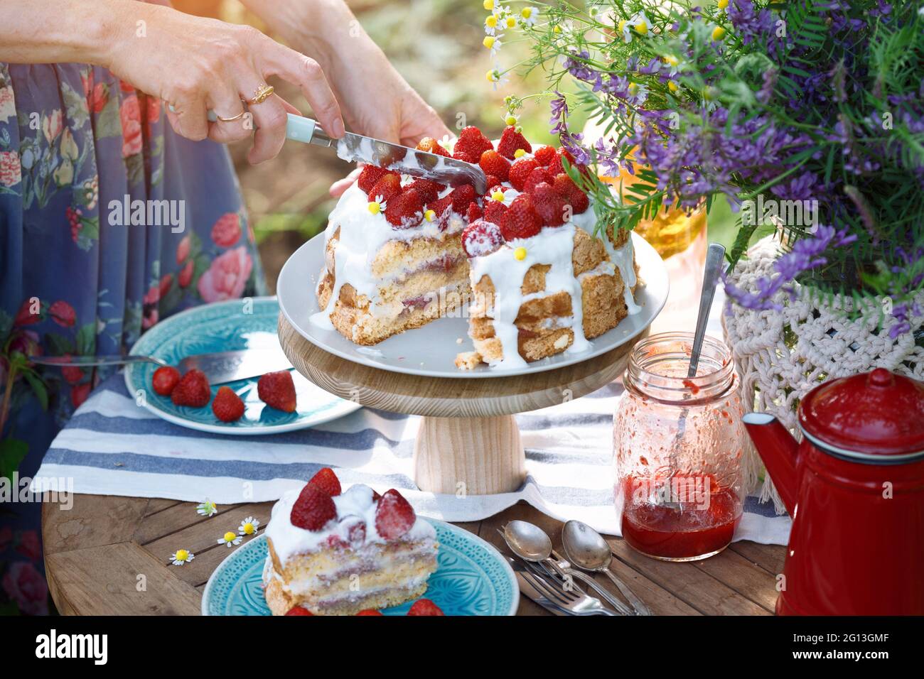 girl cuts biscuit with strawberries. dining table in the garden Stock ...
