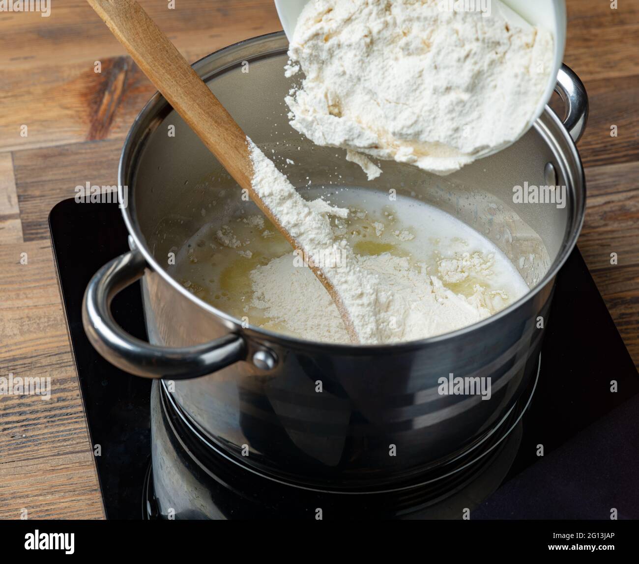 flour is poured into a pot with hot water and butter for making eclair ...