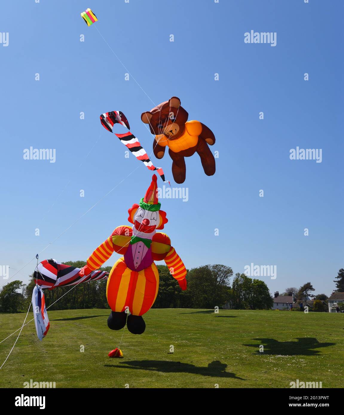 Teddy Bear and Clown Kites airborne blue sky grass and trees Stock ...