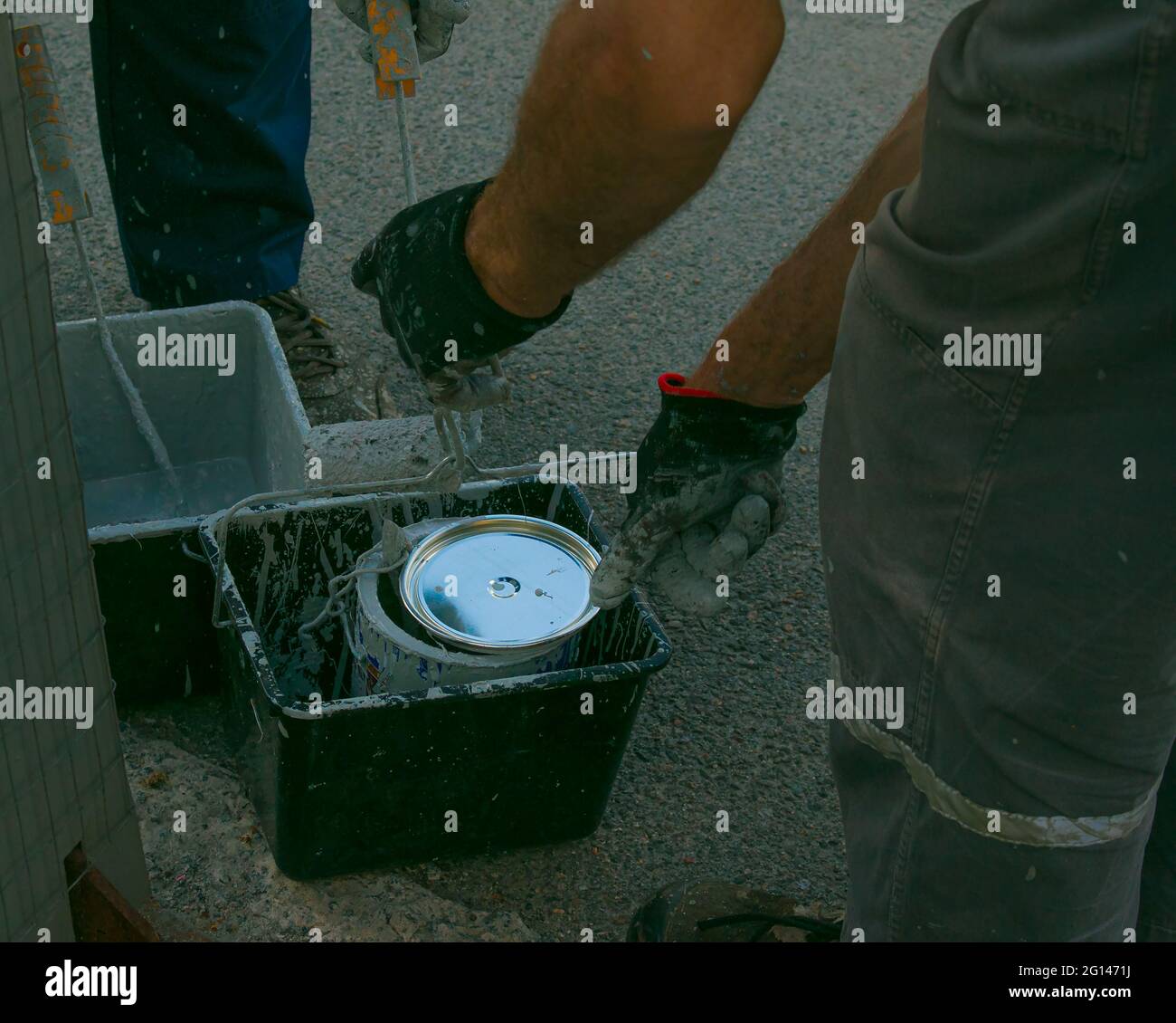 Working painters prepare paint for painting a traffic light pole. The ...