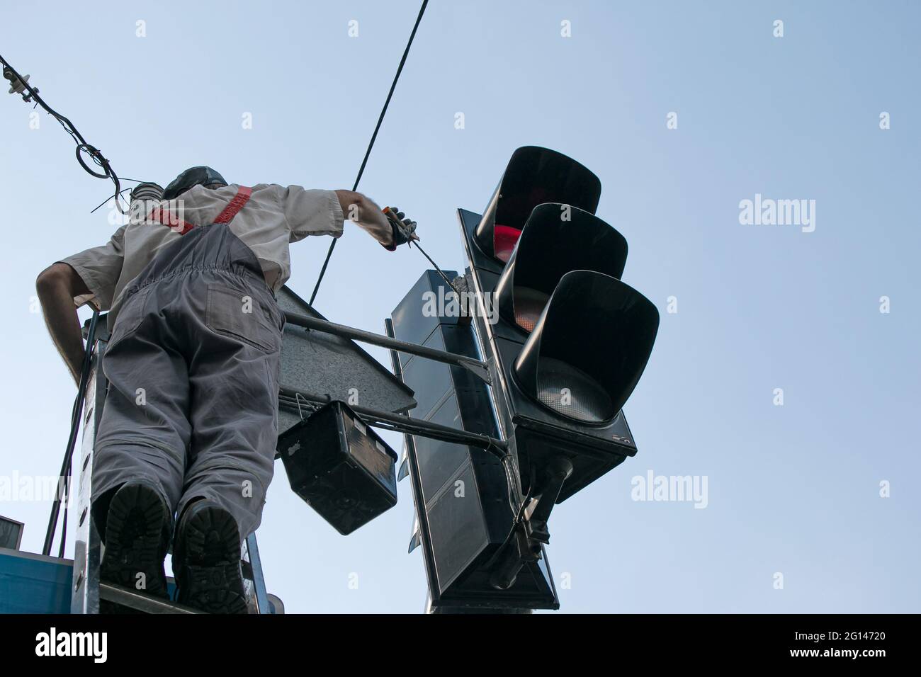 Workers of the city utilities are painting a working traffic light. An ...