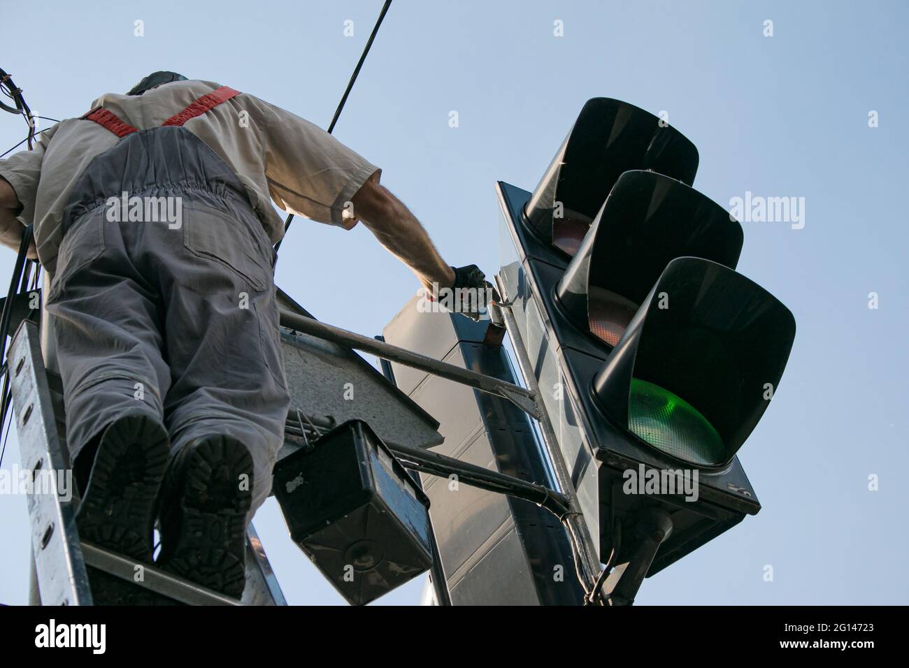 Workers of the city utilities are painting a working traffic light. An ...