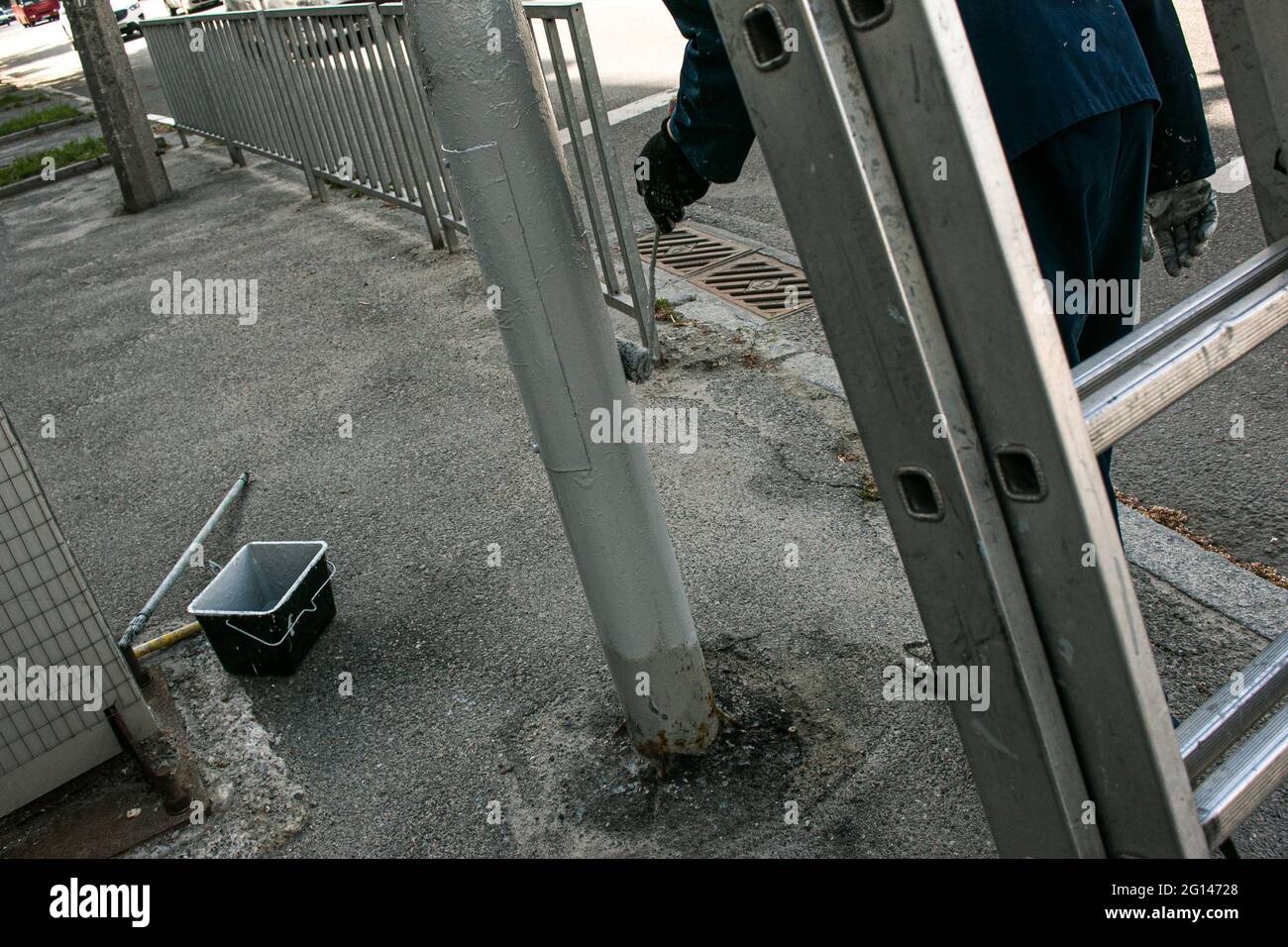 Working painters prepare paint for painting a traffic light pole. The ...