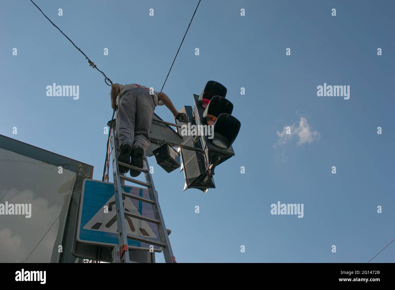 Workers of the city utilities are painting a working traffic light. An ...