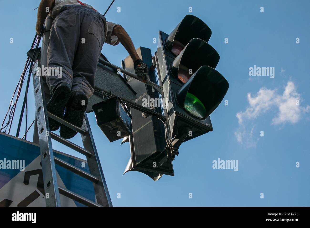 Workers of the city utilities are painting a working traffic light. An ...