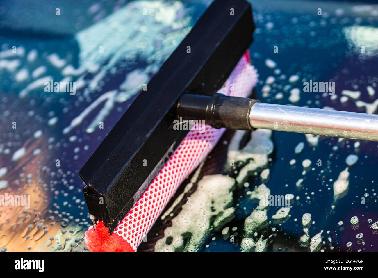 Washing and cleaning the front window of a car with mop in self service ...