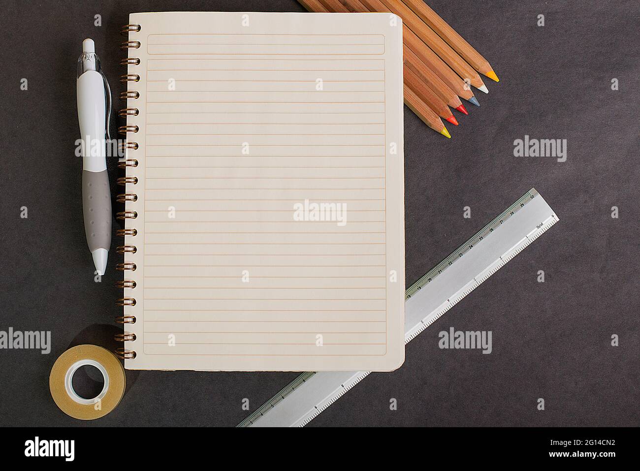 Closeup shot of an empty notebook, a pen, colored pencils, a ruler and ...