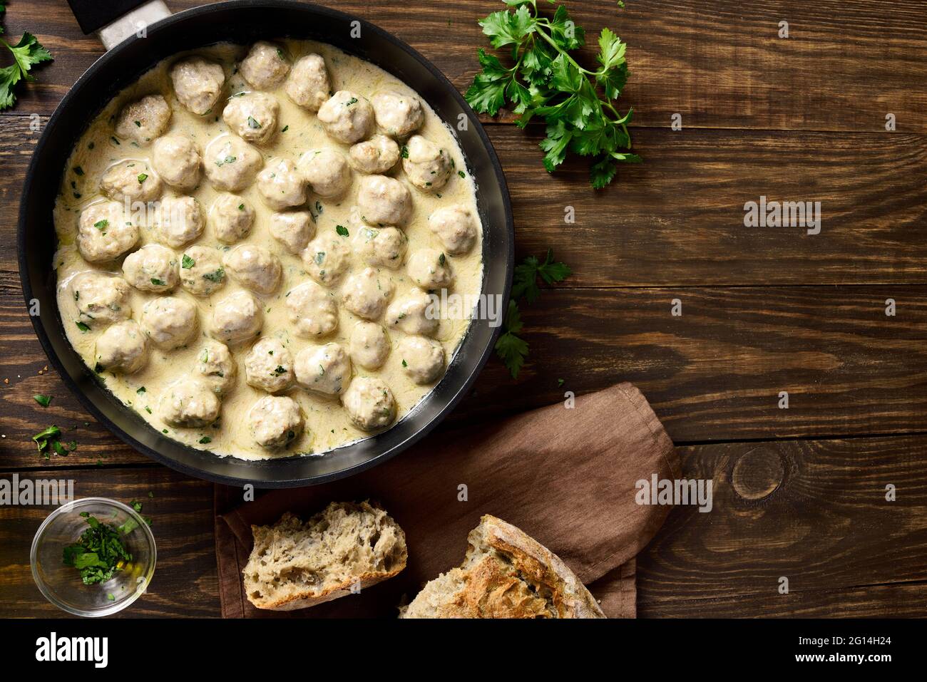 Swedish meatballs with creamy white sauce in frying pan over wooden ...