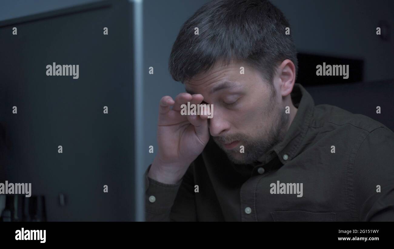 Tired male working on computer. Sad exhausted man at home office ...