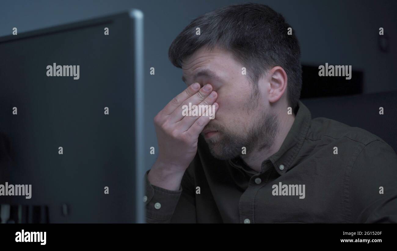 Tired male working on computer. Sad exhausted man at home office ...