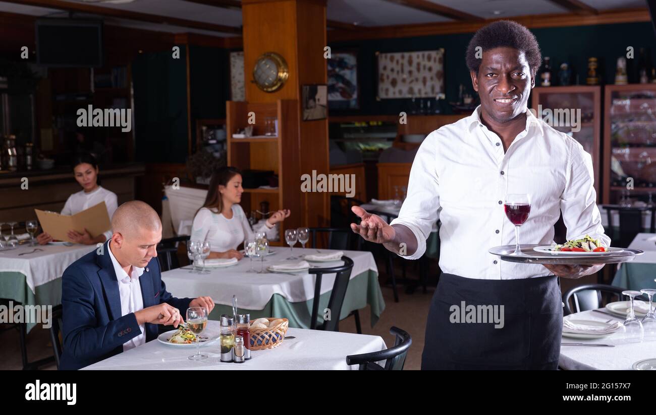 Hospitable african american waiter greeting guests in restaurant Stock ...
