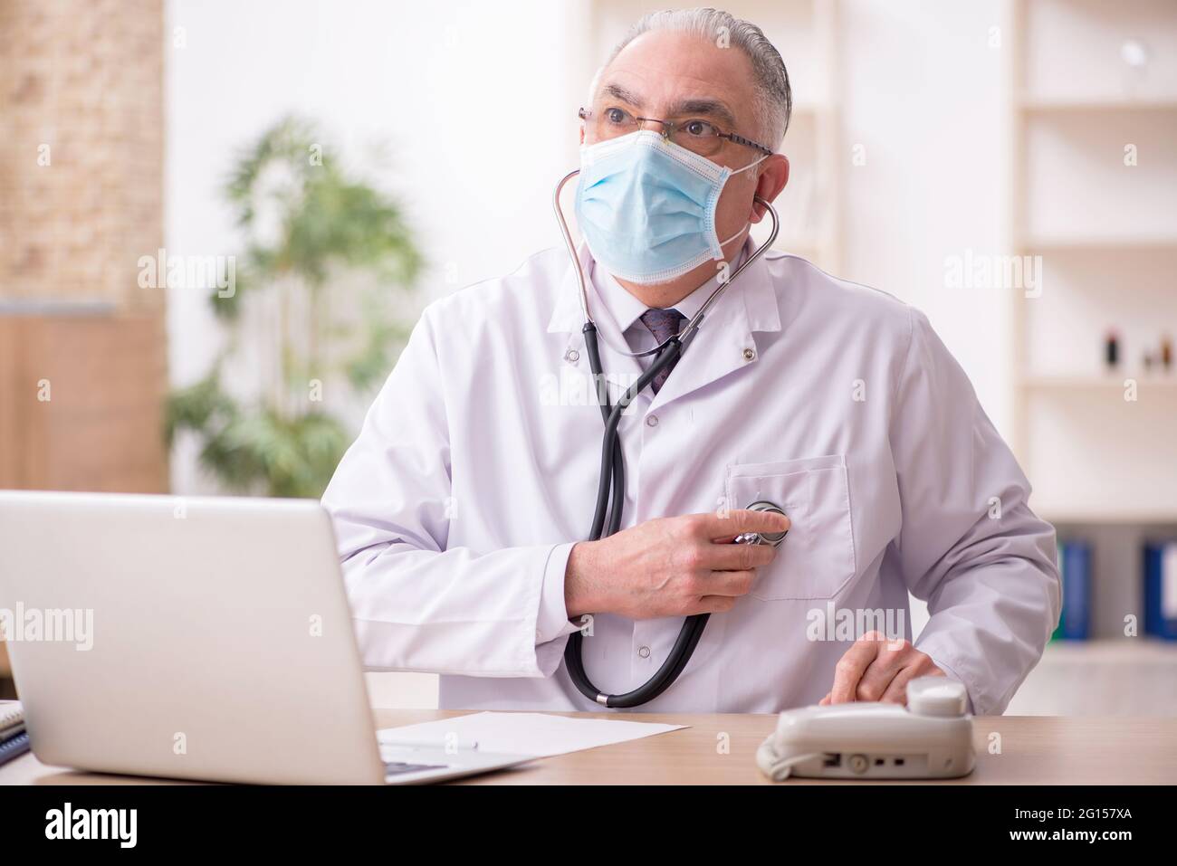 Old doctor working in the clinic during pandemic Stock Photo - Alamy