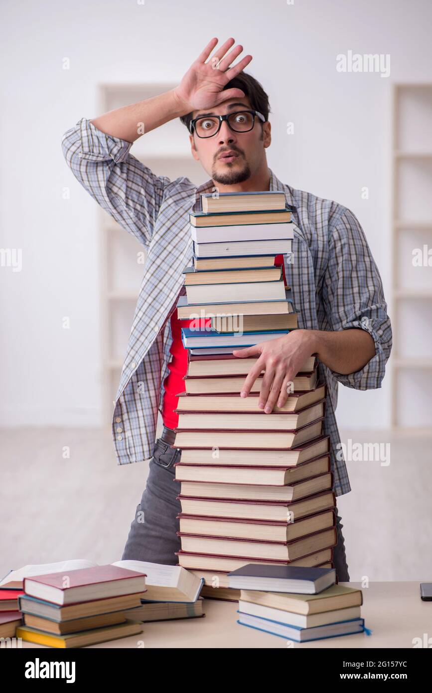 Young student and too many books in the classroom Stock Photo - Alamy