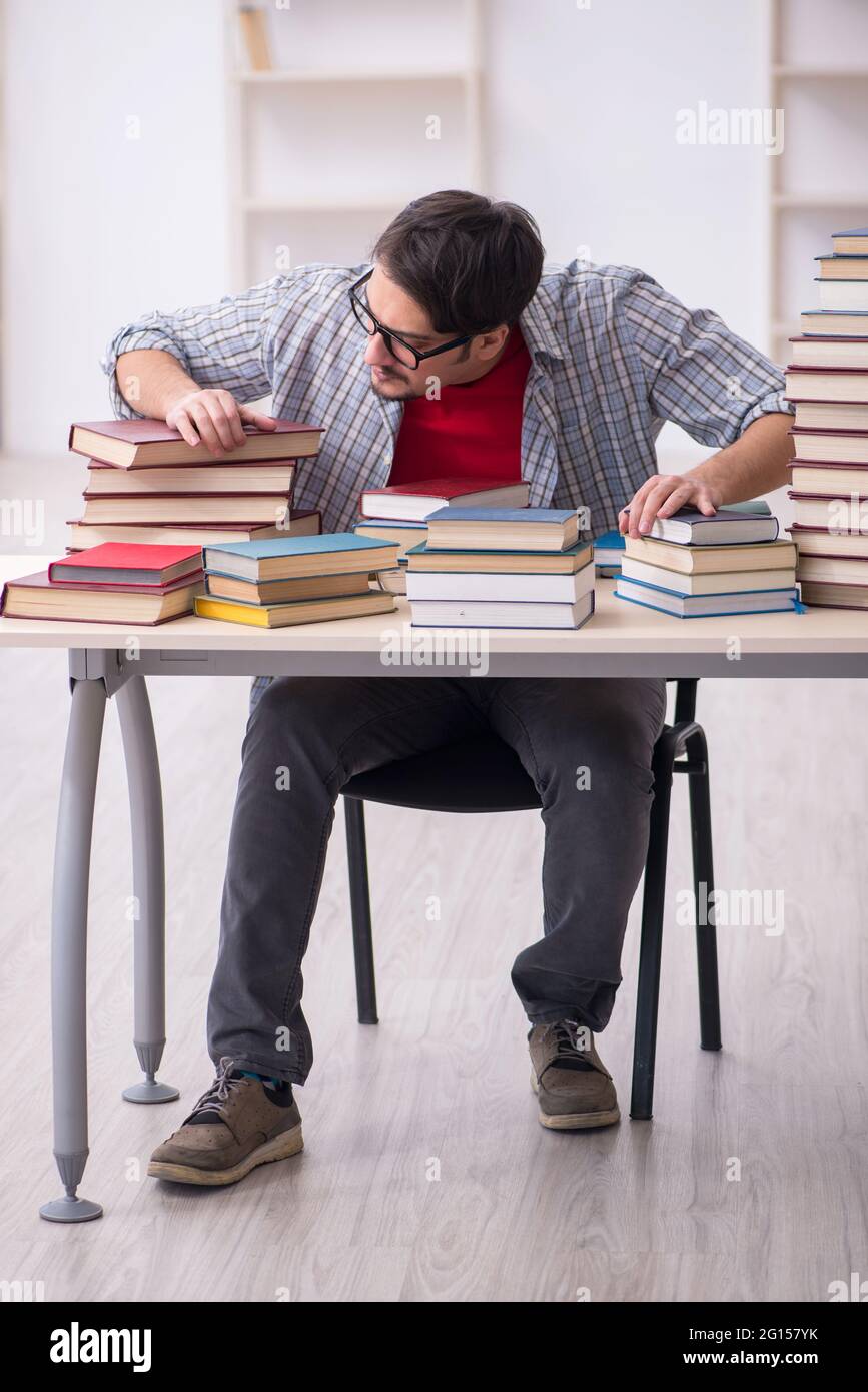 Young student and too many books in the classroom Stock Photo - Alamy