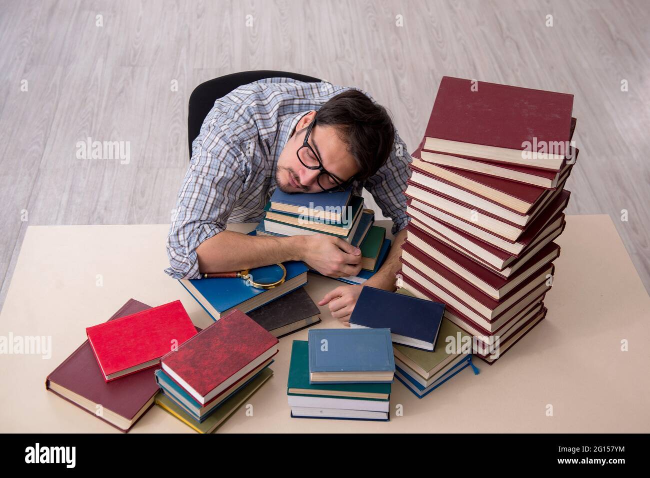 Young student and too many books in the classroom Stock Photo - Alamy