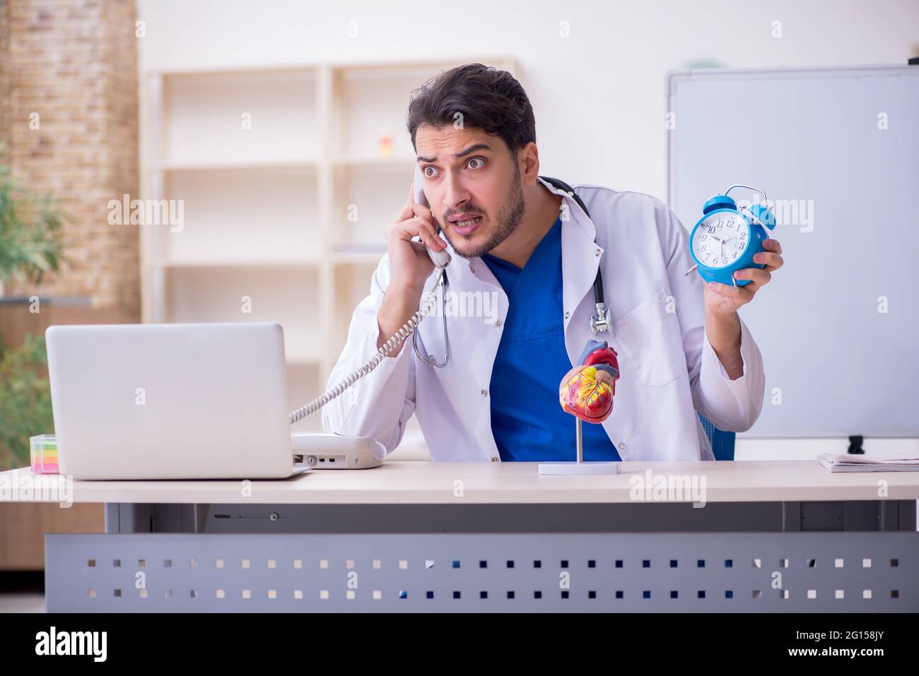 Young doctor cardiologist in time management concept Stock Photo - Alamy
