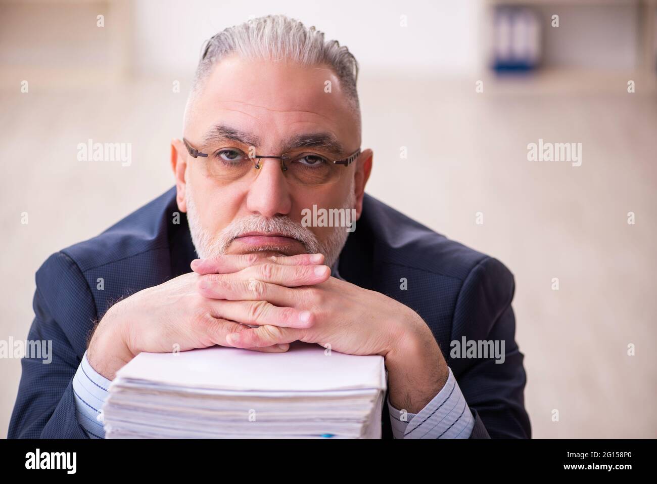 Old male employee unhappy with excessive work at workplace Stock Photo ...