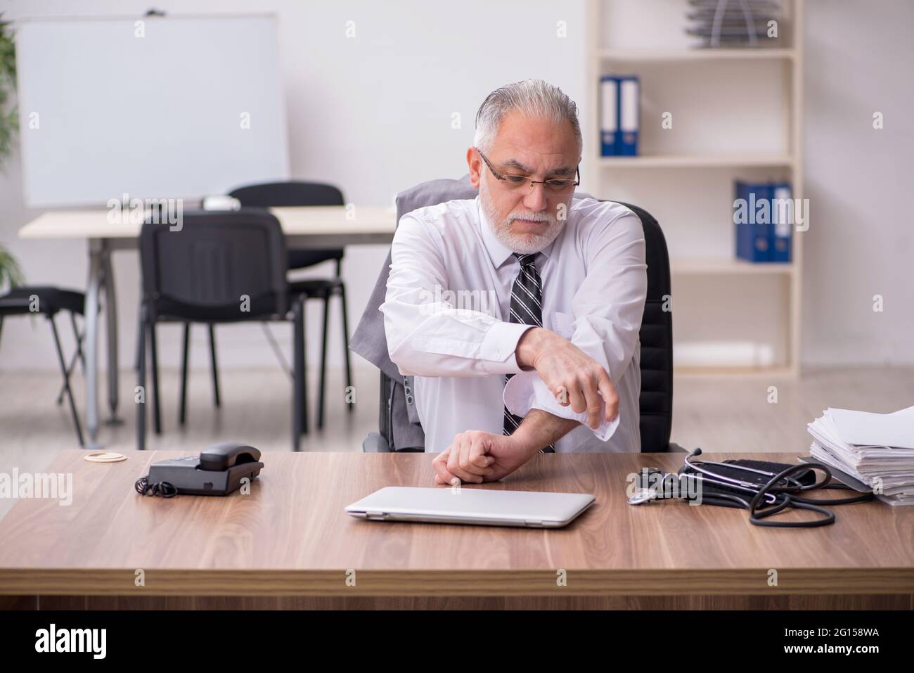 Aged male employee feeling bad in the office Stock Photo - Alamy