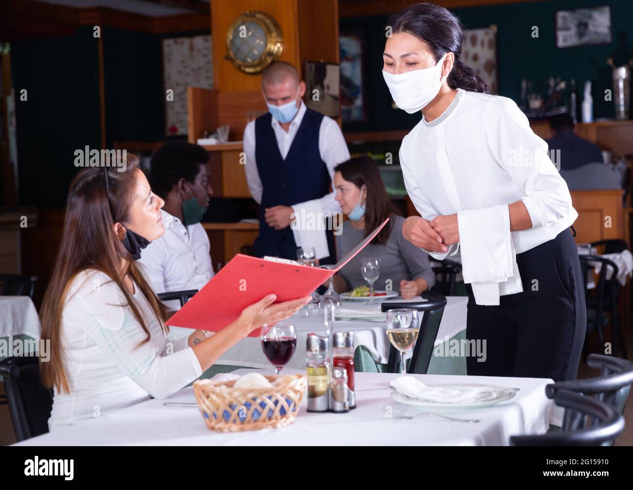smiling female waiter taking order from woman in restaurante diring ...