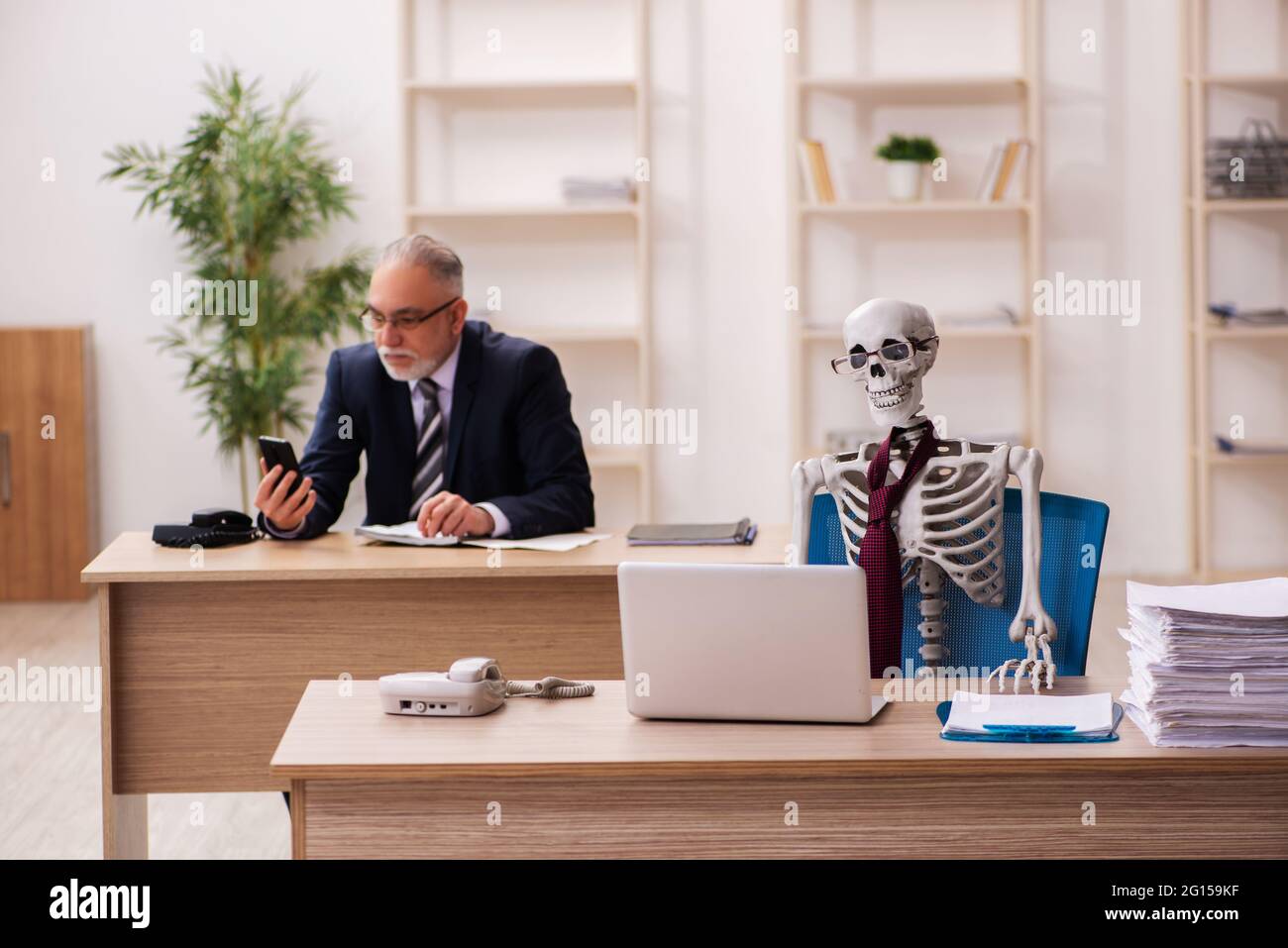 Dead employee working in the office in funny concept Stock Photo - Alamy