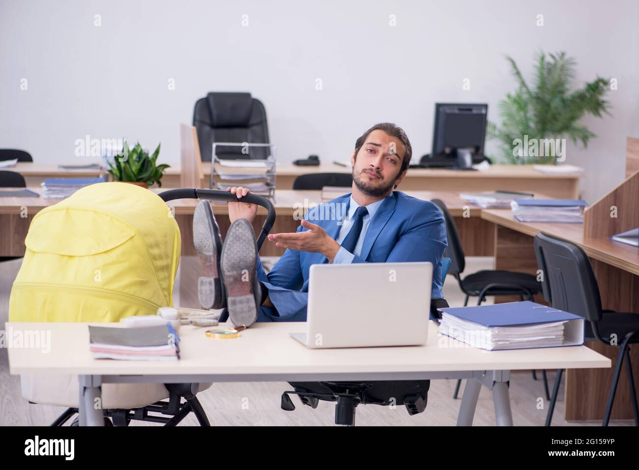 Young male employee looking after new born in the office Stock Photo ...