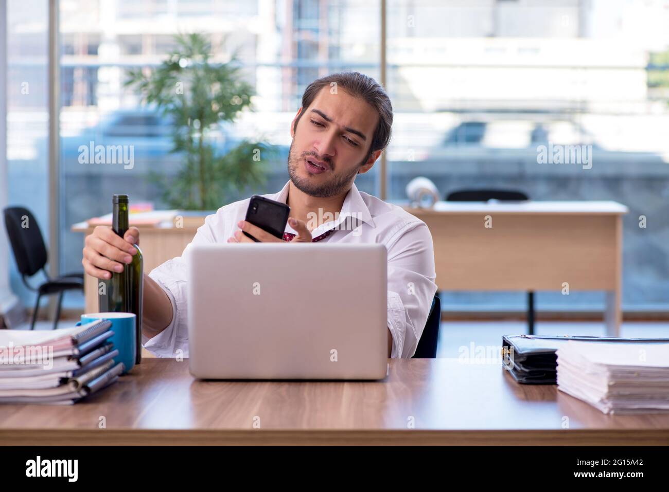 Young alcohol addicted employee working in the office Stock Photo - Alamy