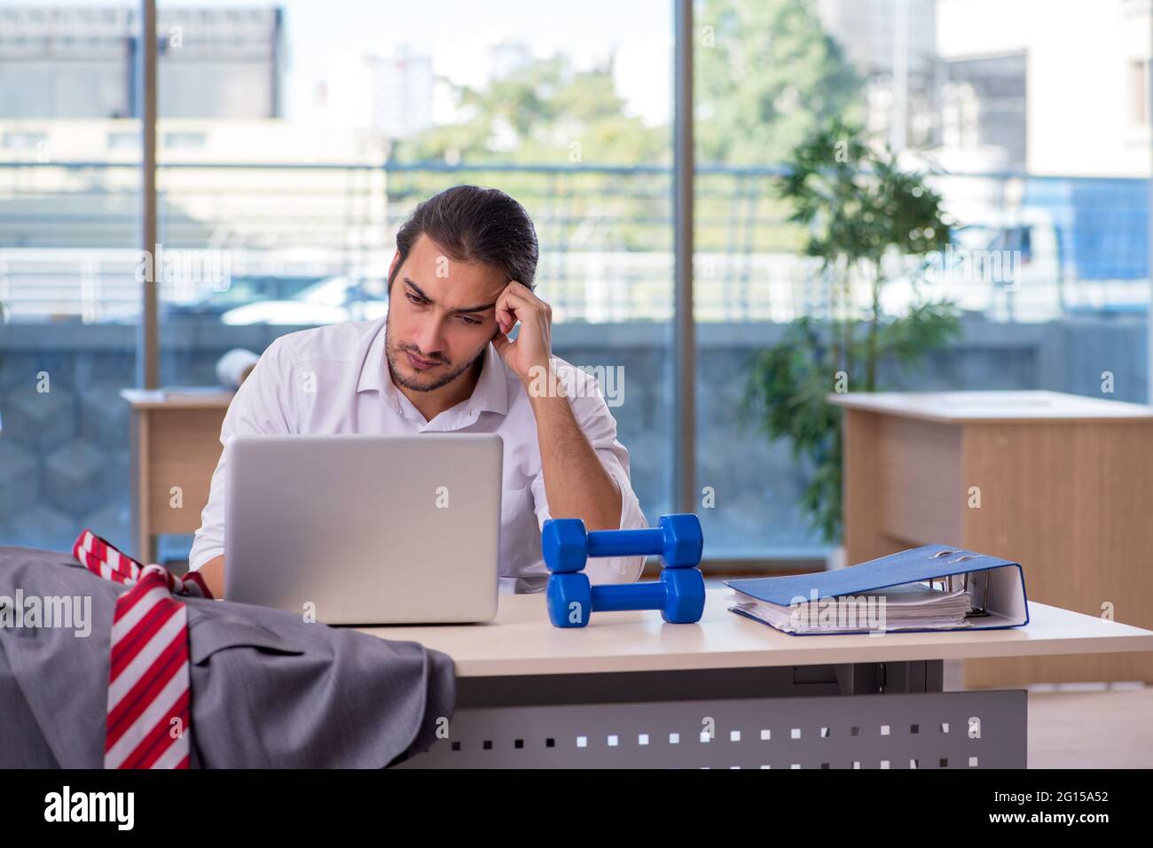 Young employee doing sport exercises at workplace Stock Photo - Alamy
