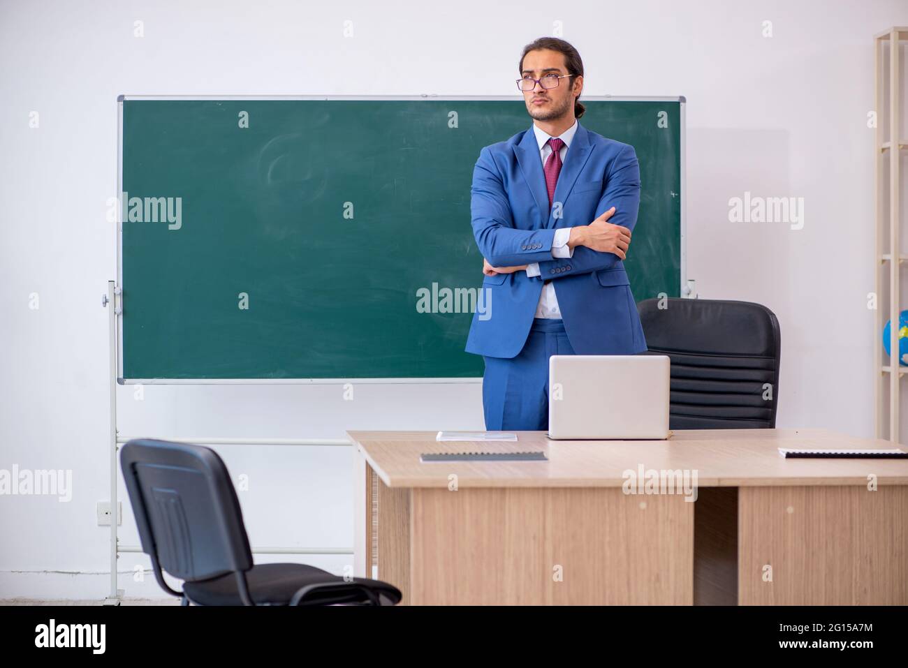 Young teacher in suit in front of green board Stock Photo - Alamy