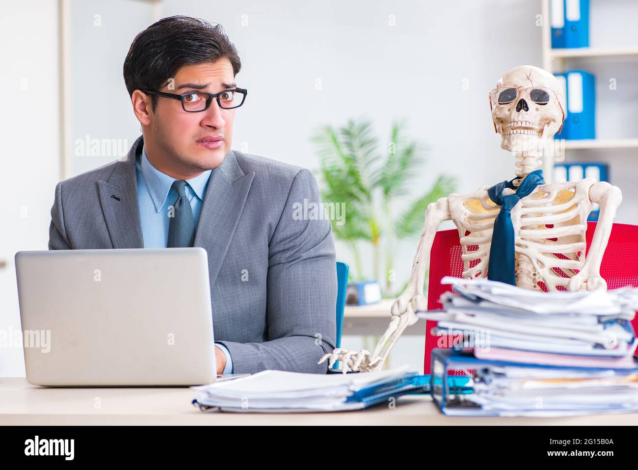 The businessman working with skeleton in office Stock Photo - Alamy