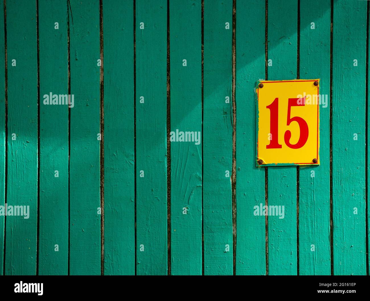 Green flaky paint on an old weathered wooden wall with plate number ...