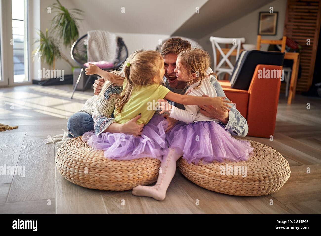 A young excited family in a hug while playing in a joyful atmosphere at ...