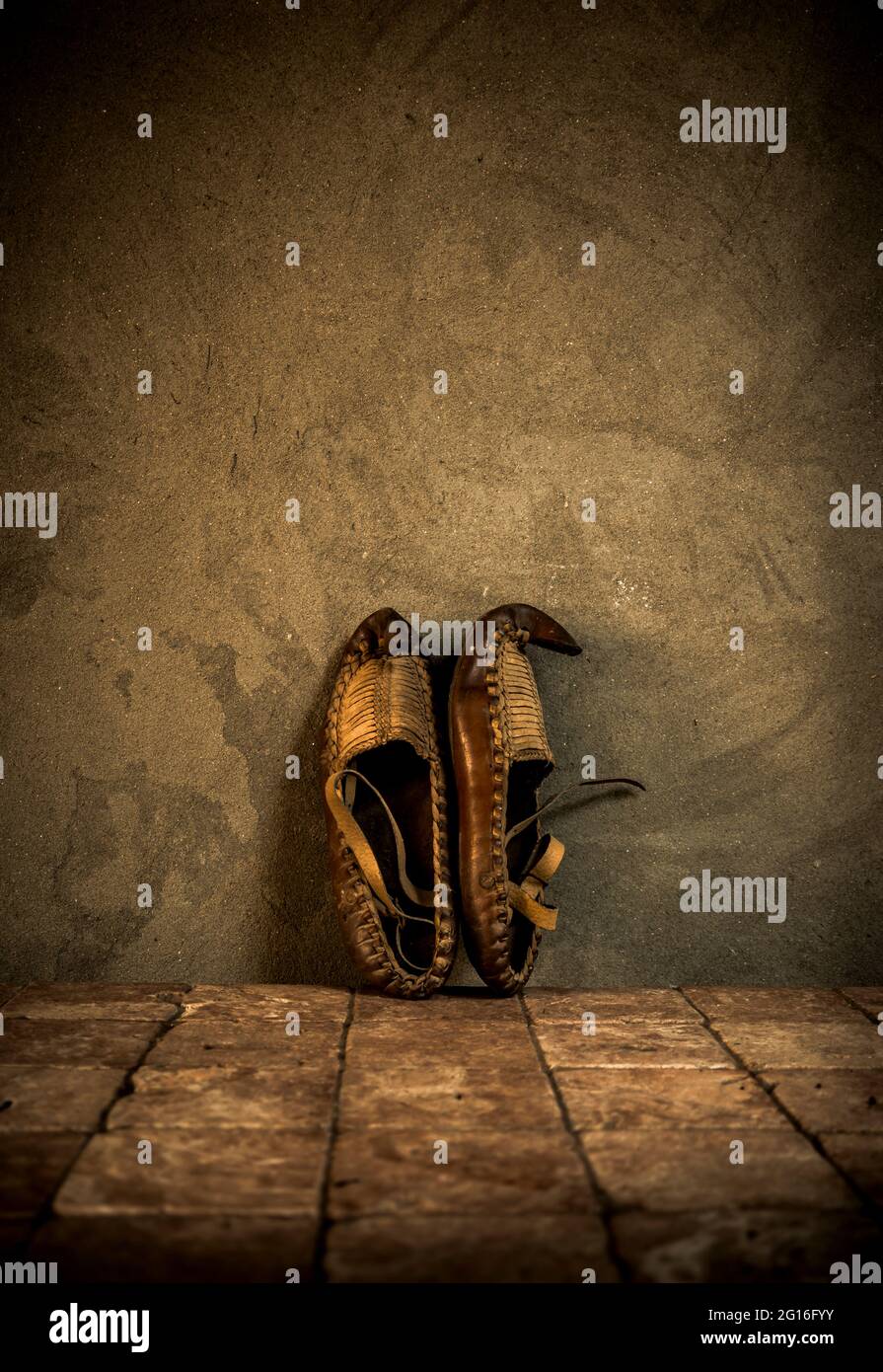 Old rustic footwear made of leather on antique tiles and concrete wall ...