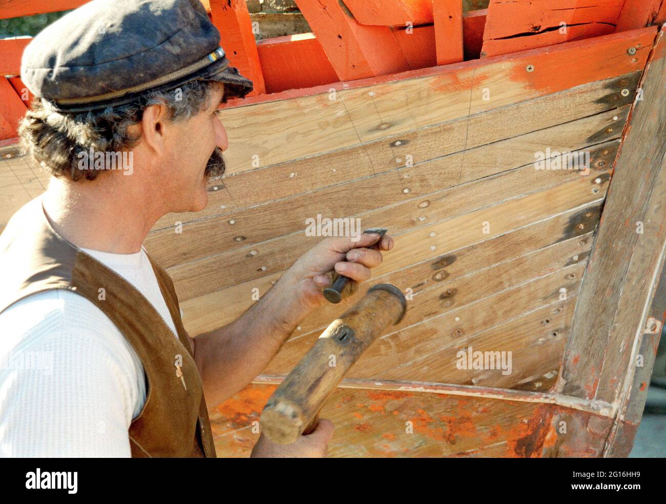 Shipwright caulking a wooden fishing boat Stock Photo - Alamy