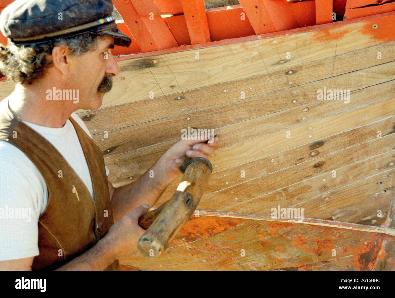 Shipwright caulking a wooden fishing boat Stock Photo - Alamy