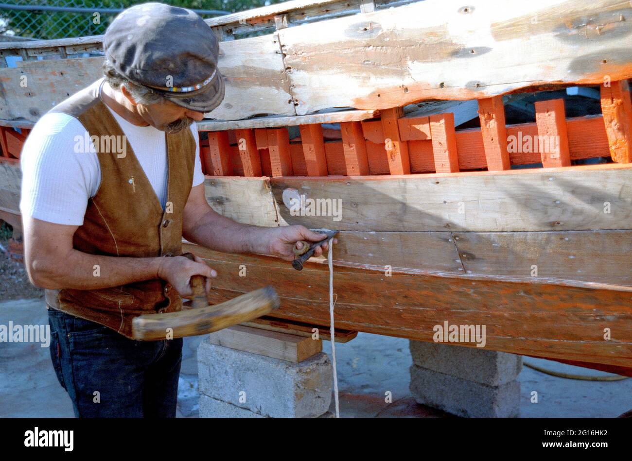 Shipwright caulking a wooden fishing boat Stock Photo - Alamy