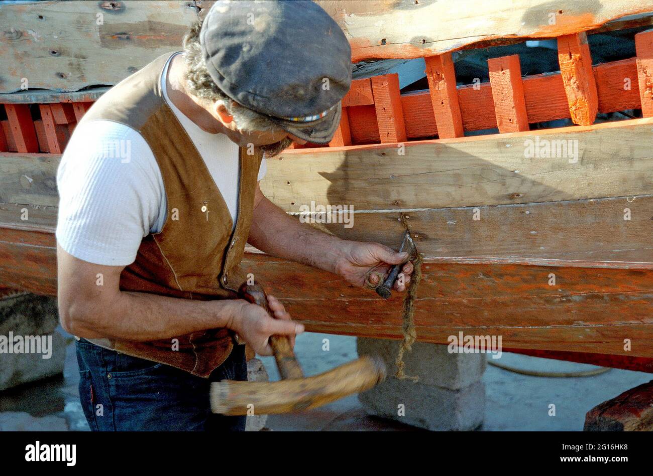 Shipwright caulking a wooden fishing boat Stock Photo - Alamy
