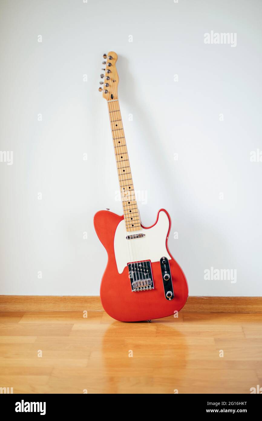 Red electric guitar on white wall Stock Photo - Alamy