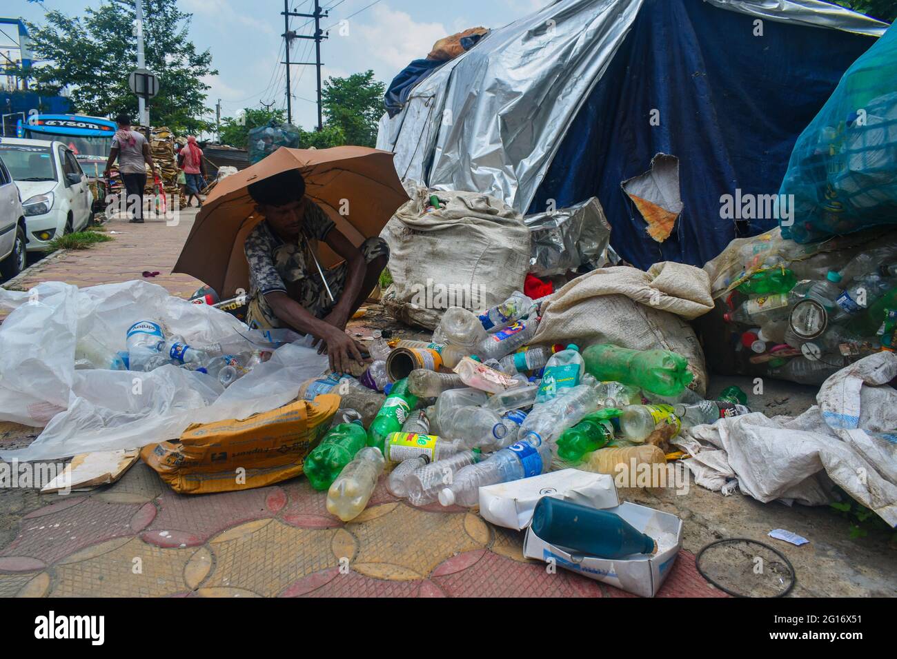 A person is collecting the used plastic bottles inside a garbage yard ...