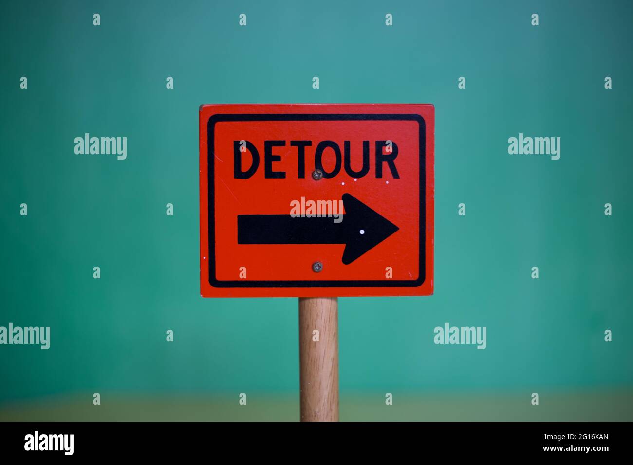 Closeup shot of a red "Detour" sign with a black arrow indicating ...
