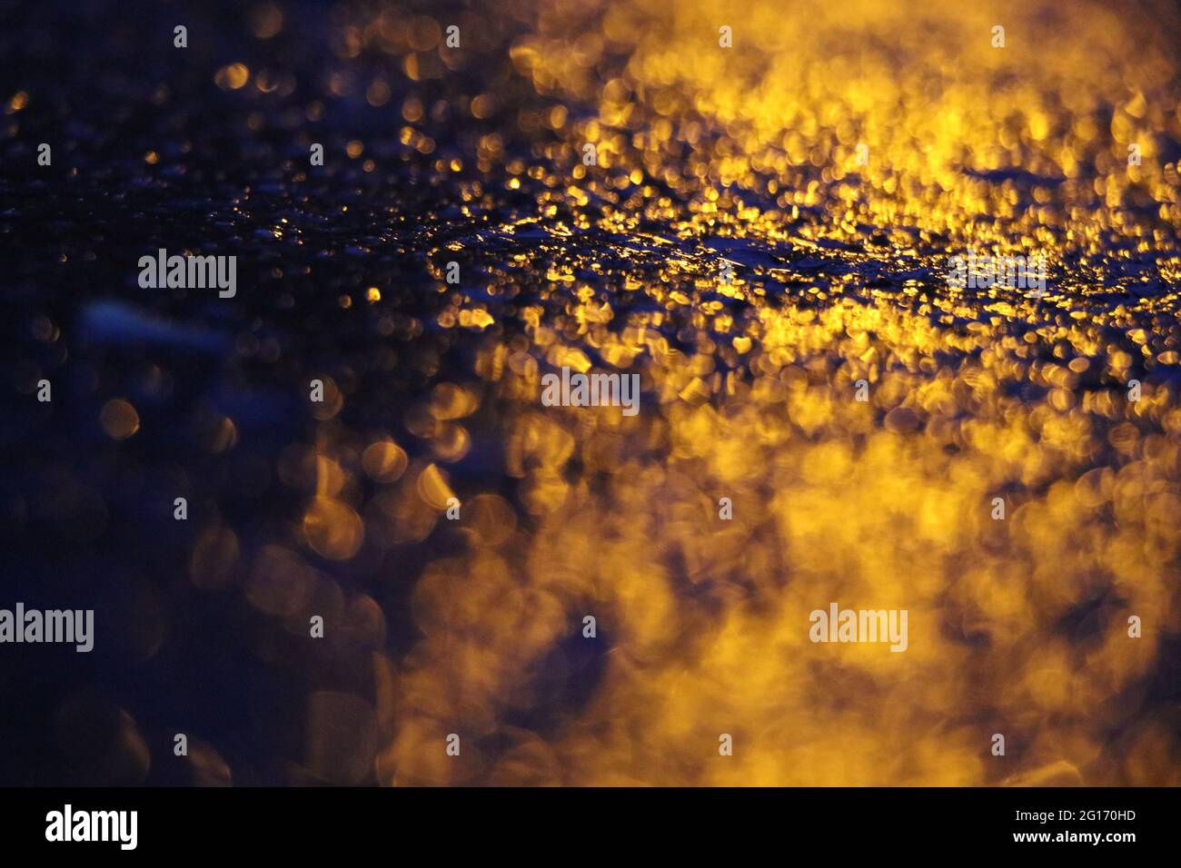 abstract image of yellow light reflecting off uneven black surface ...