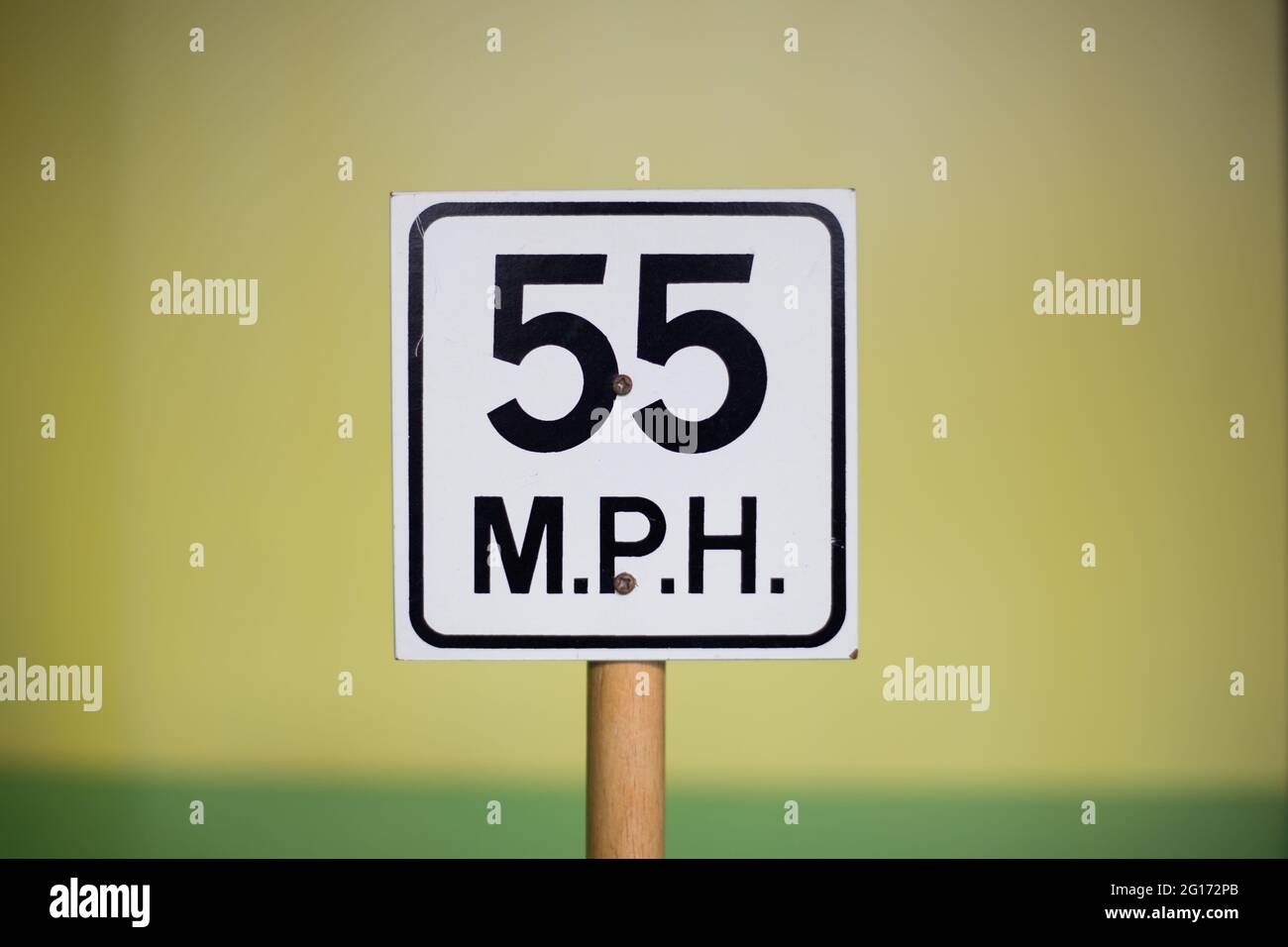 Closeup shot of a sign indicating the speed limit of 55 on a blurred ...