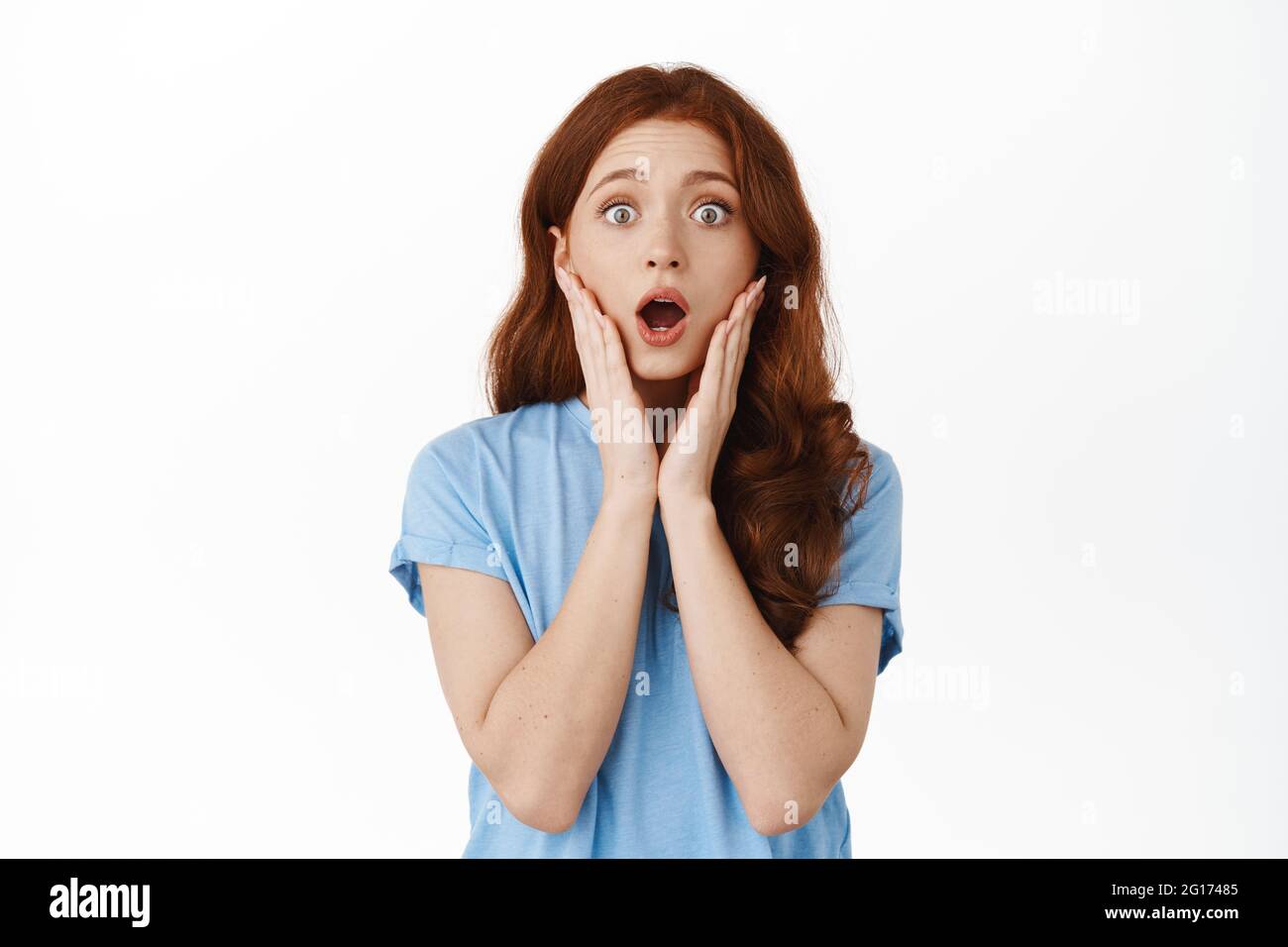 Surprised redhead woman drop jaw, gasp and say wow, staring in awe at ...