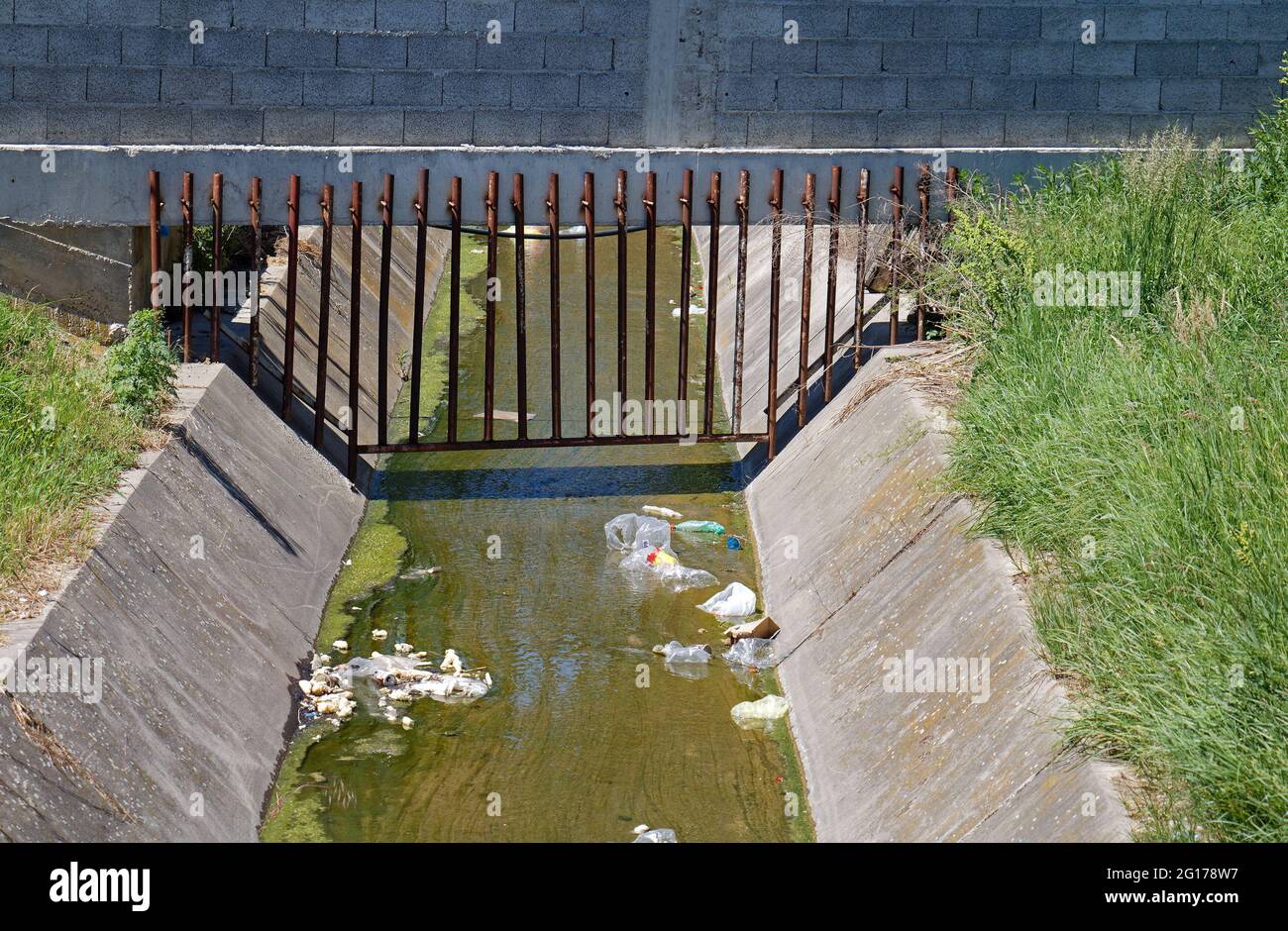 Small water canal outdoors polluted with plastic waste floating on top ...
