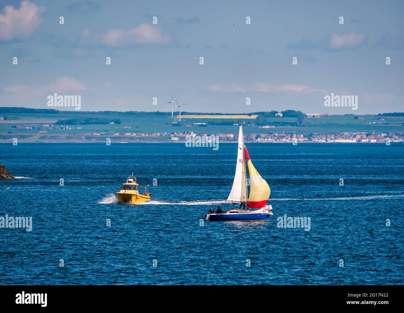 Fishing boat and sailing dinghy sailboat with spinnaker on Summer day ...
