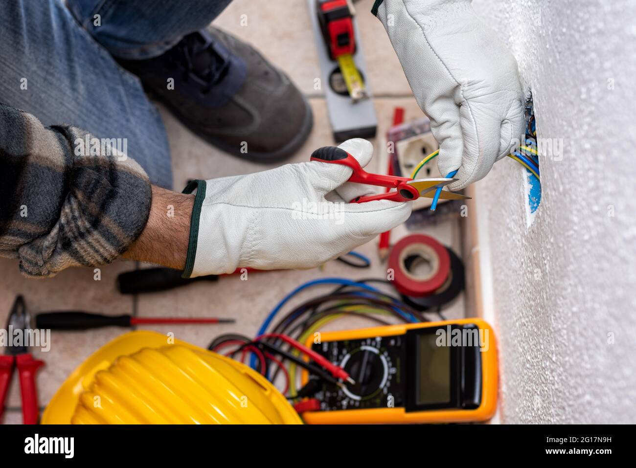 View from top. Electrician worker at work with scissors prepares the ...