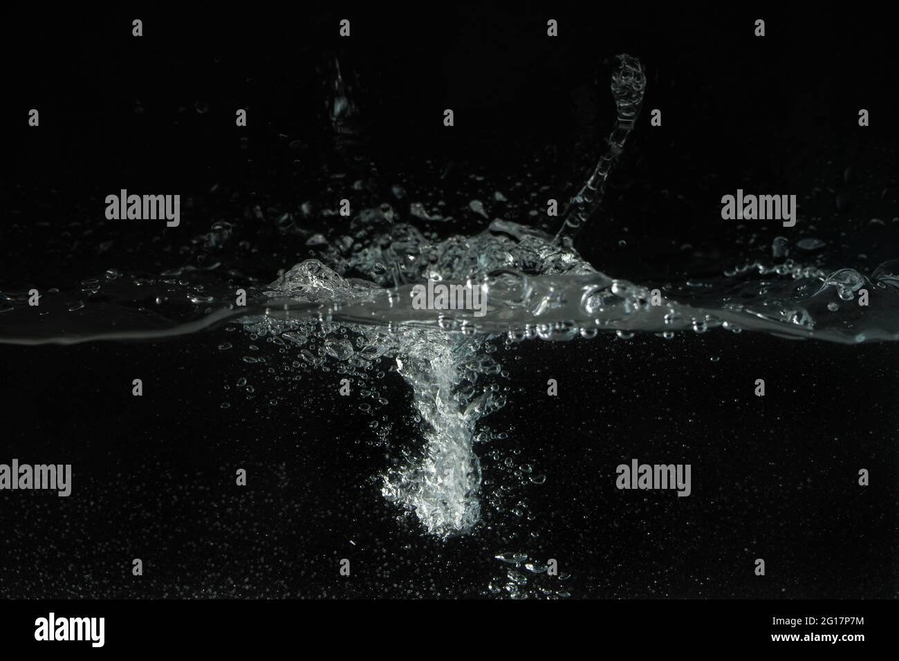 Water splashing as it's poured into aquarium tank, black background ...