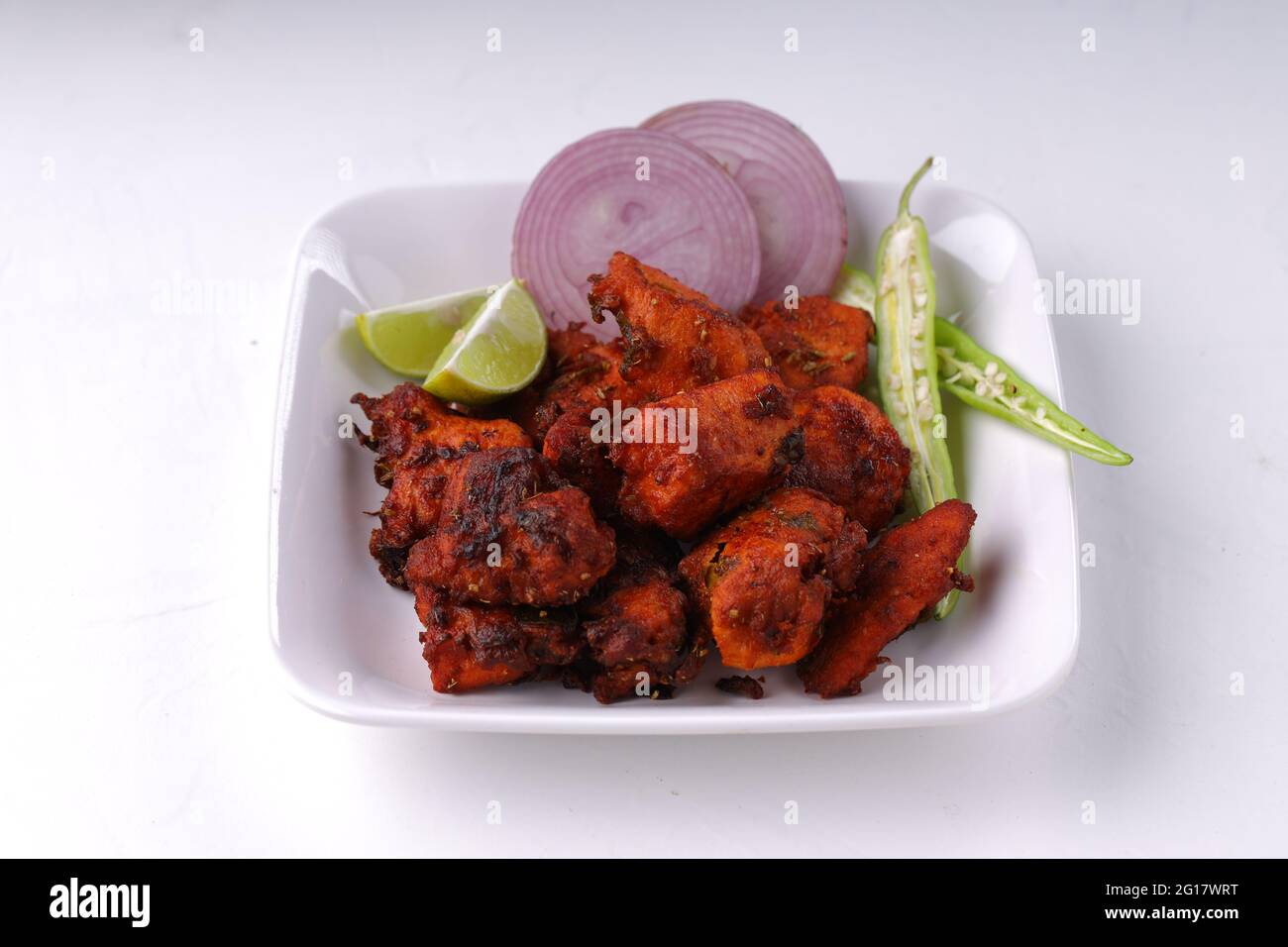 Indian Chicken fry,arranged in a white plate garnished with lemon ...