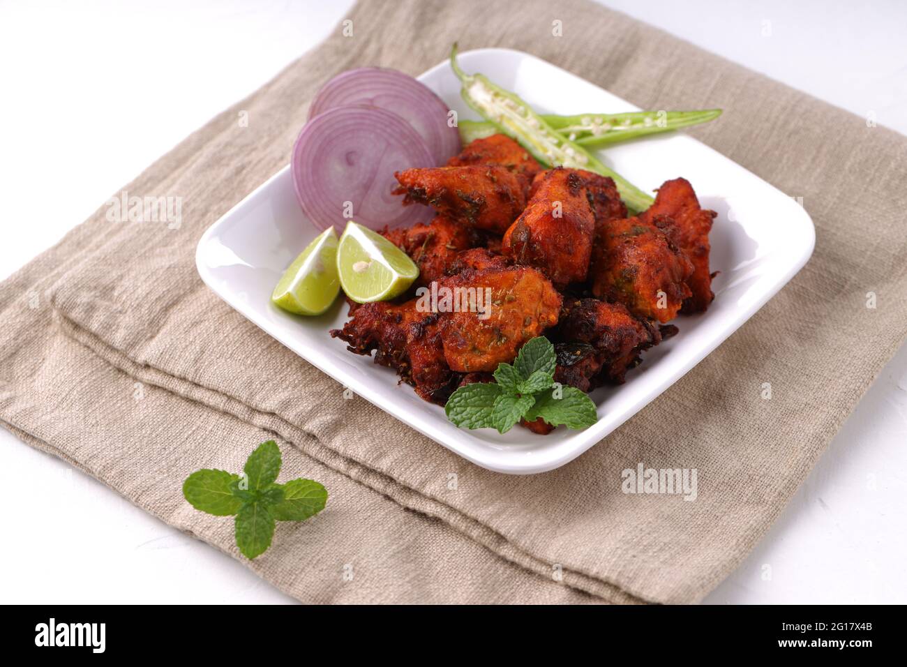 Indian Chicken fry,arranged in a white plate garnished with lemon ...