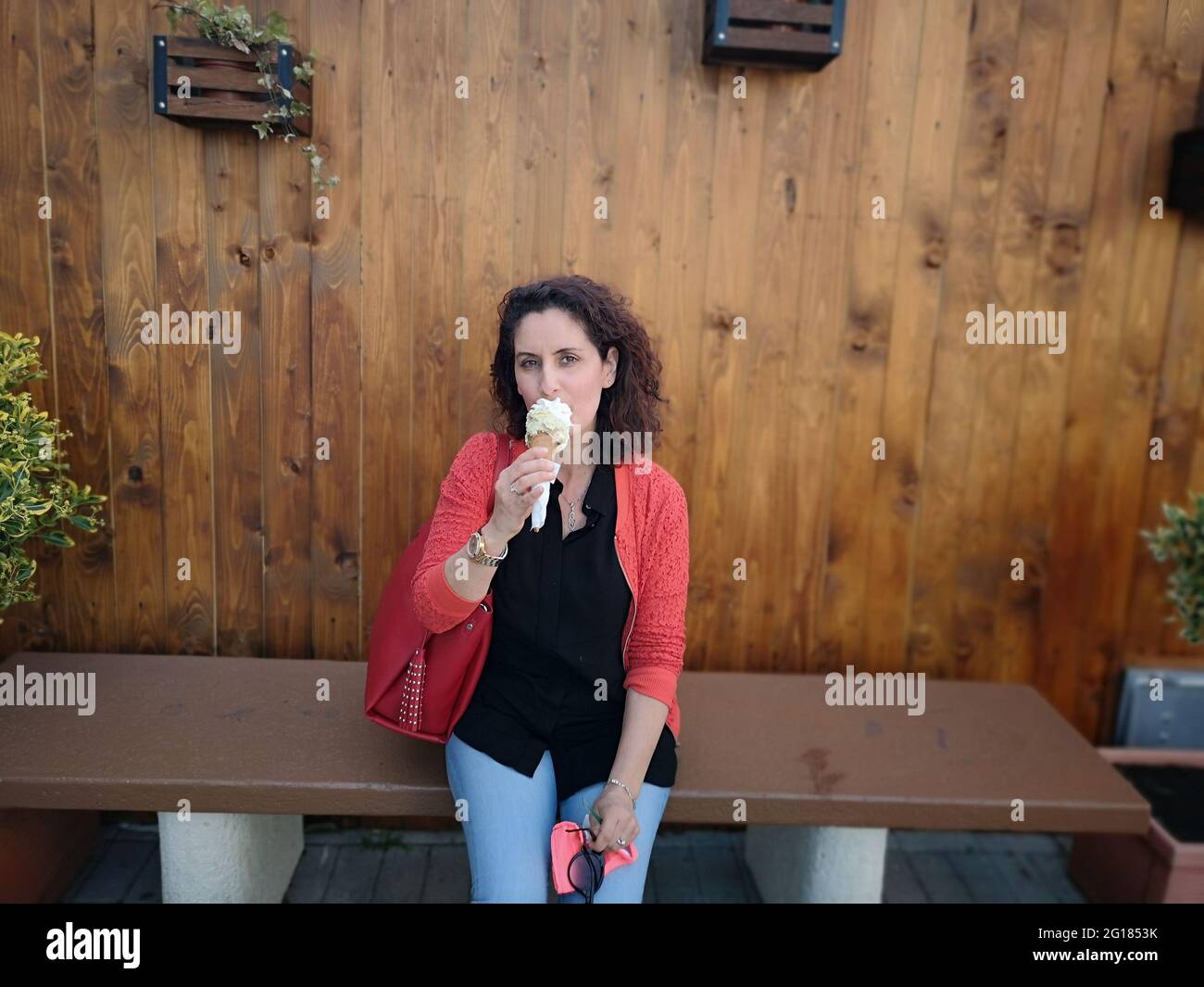 Caucasian female eating gelato on the bench Stock Photo - Alamy